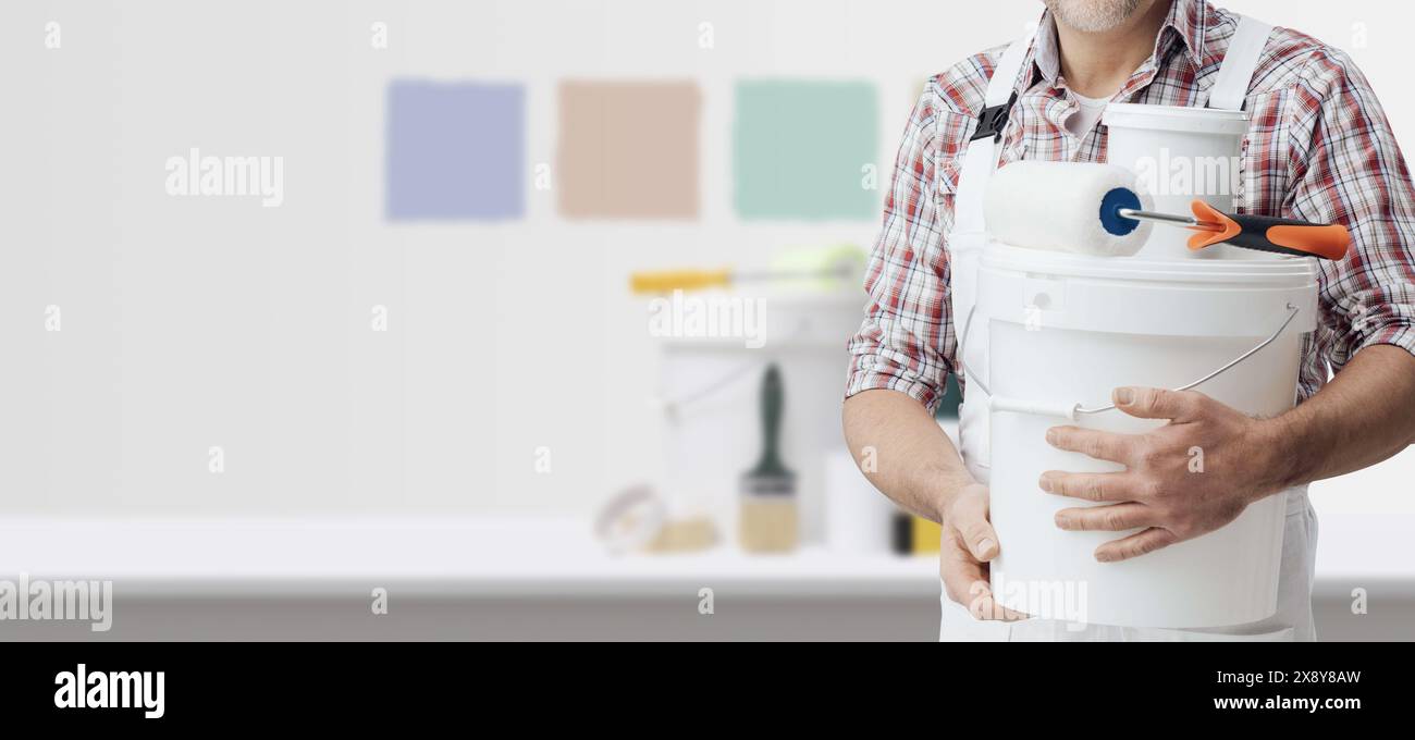 Professional painter holding paint buckets and a paint roller, painting ...