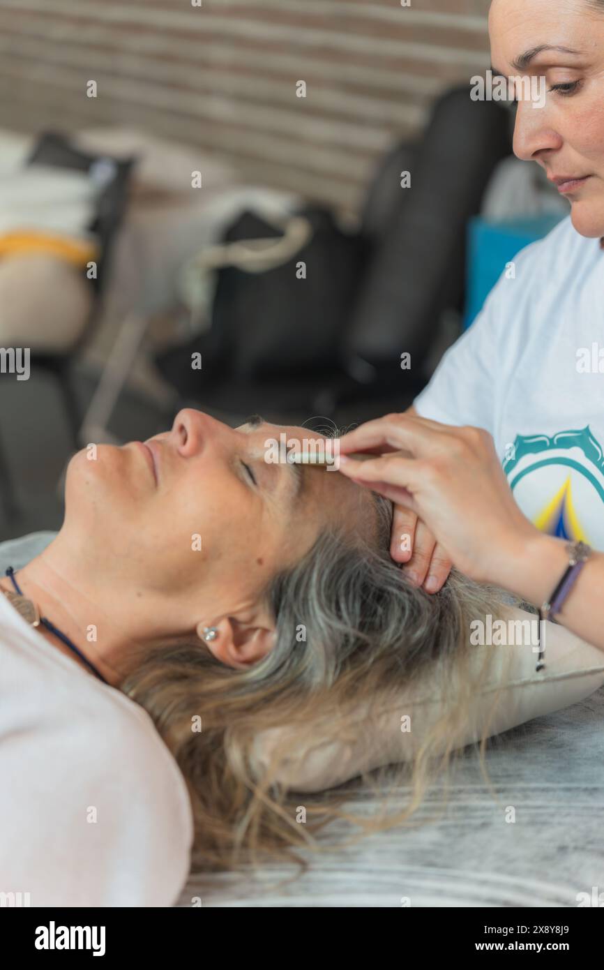 Specialist giving a face massage to an elderly woman lying on the ...