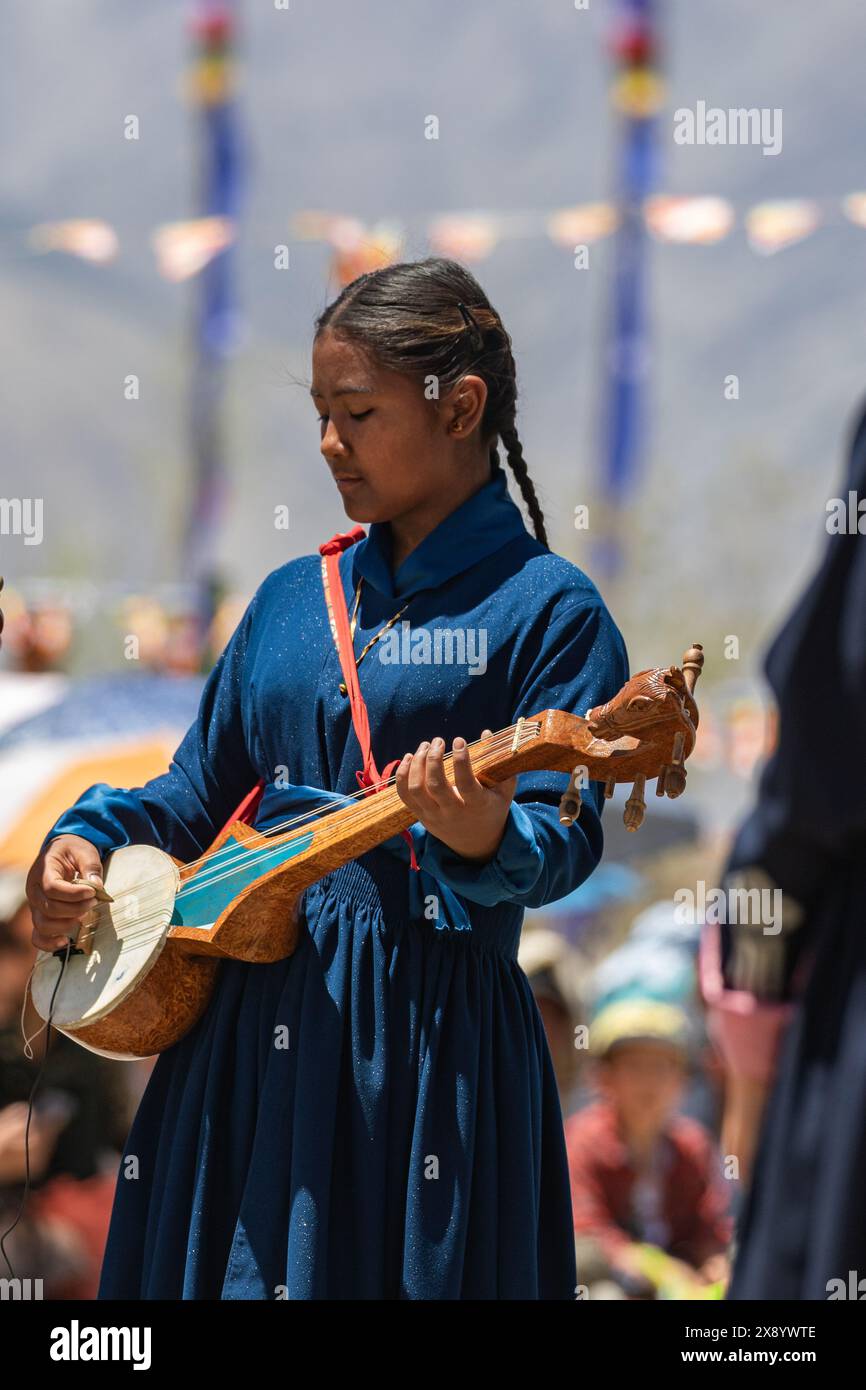 Portrait of a young Ladakhi girl in traditional attire playing a ...