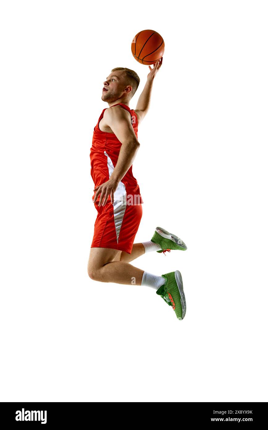 Athletic man, basketball player in red uniform jumping in mid-air ...