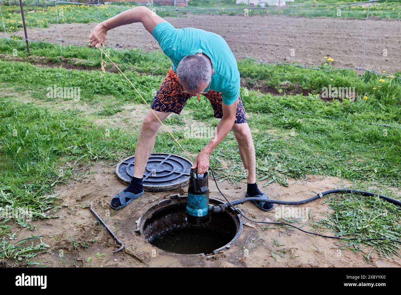 When servicing a septic tank, a man uses a submersible wastewater pump ...