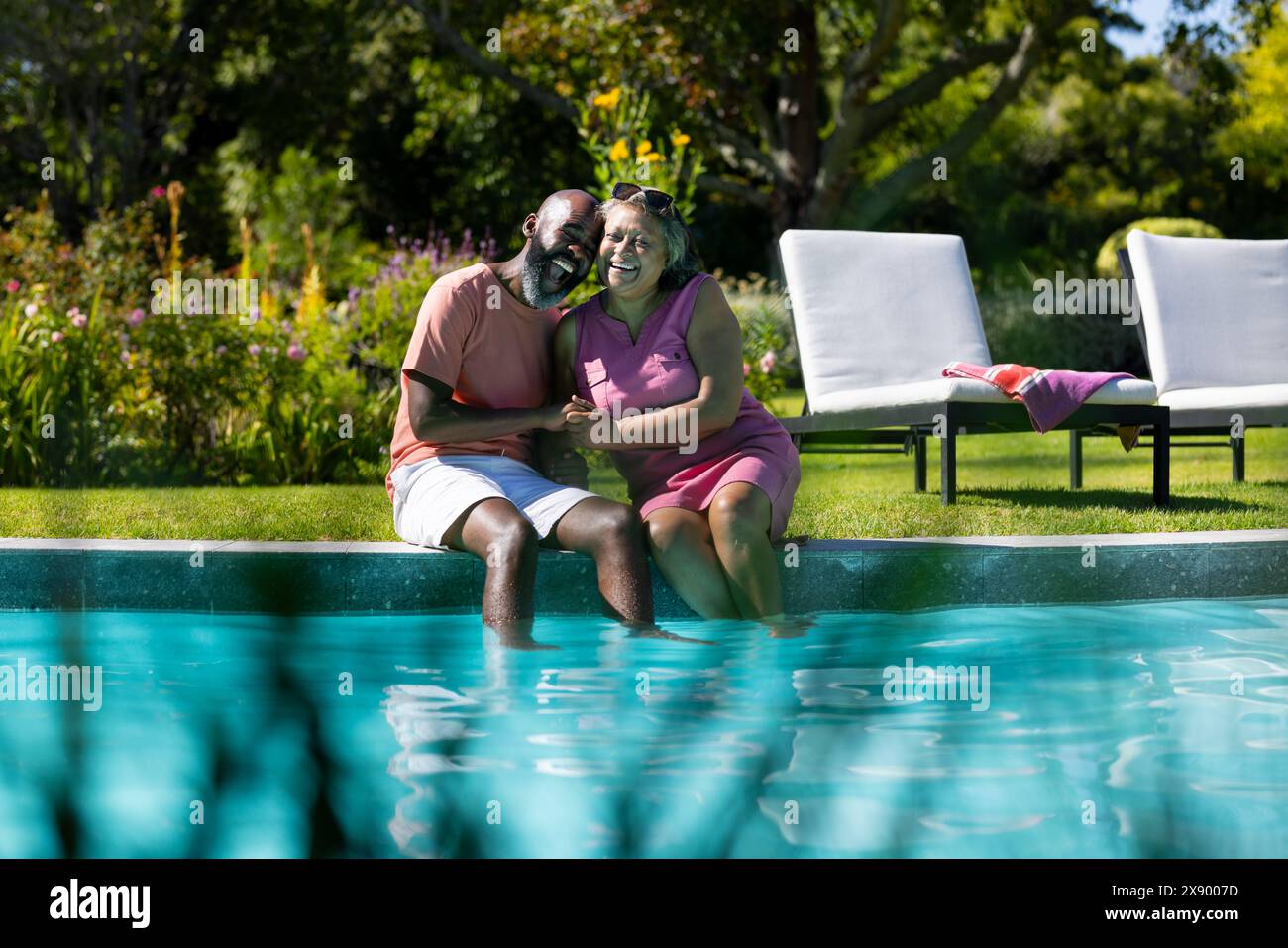Outdoors, diverse senior friends sitting by pool, laughing together ...