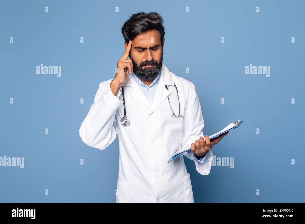 Indian Doctor Reading Medical Report With Focus Against Blue Background ...