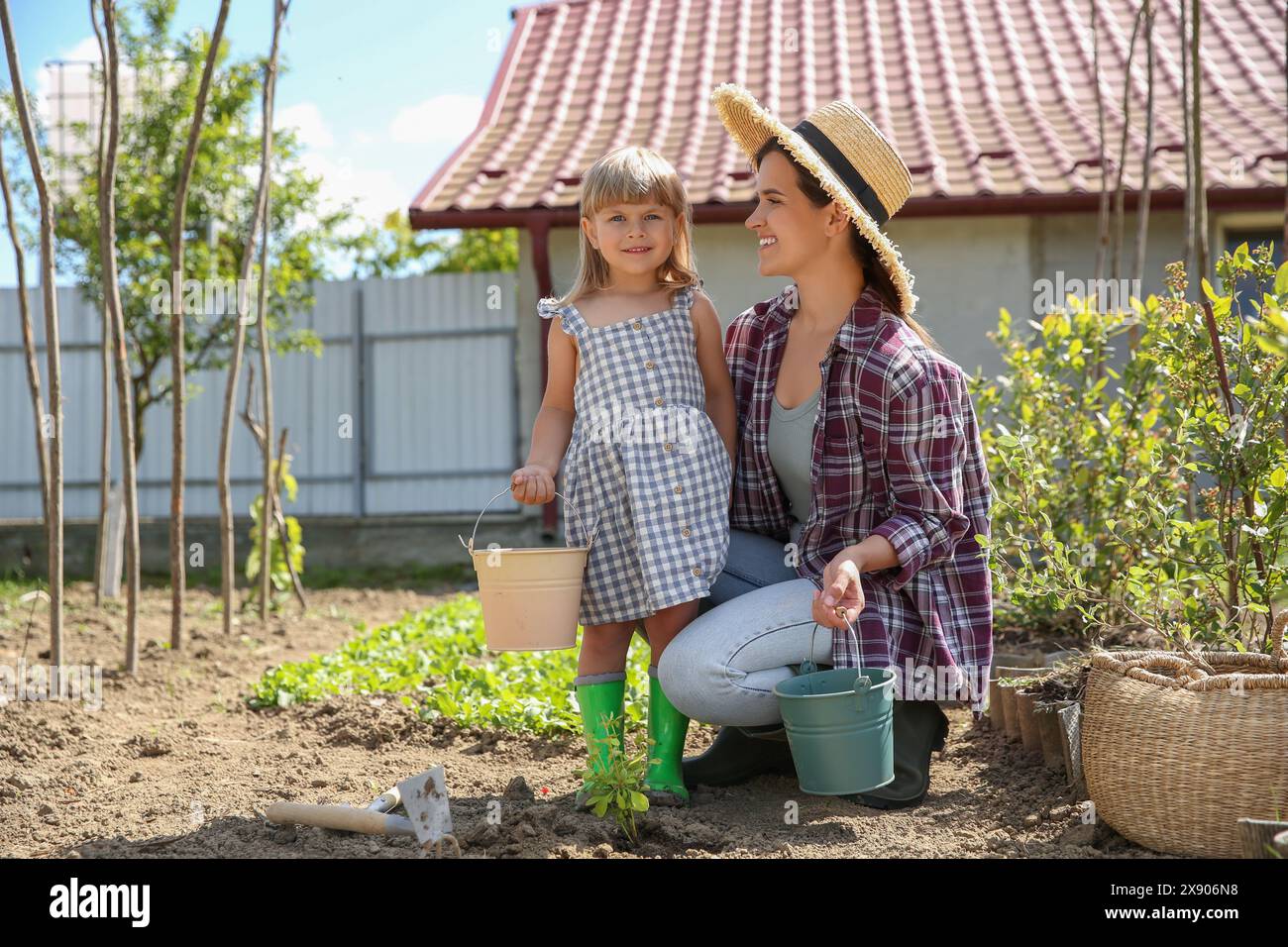 Mother and her cute daughter planting tree together in garden Stock ...