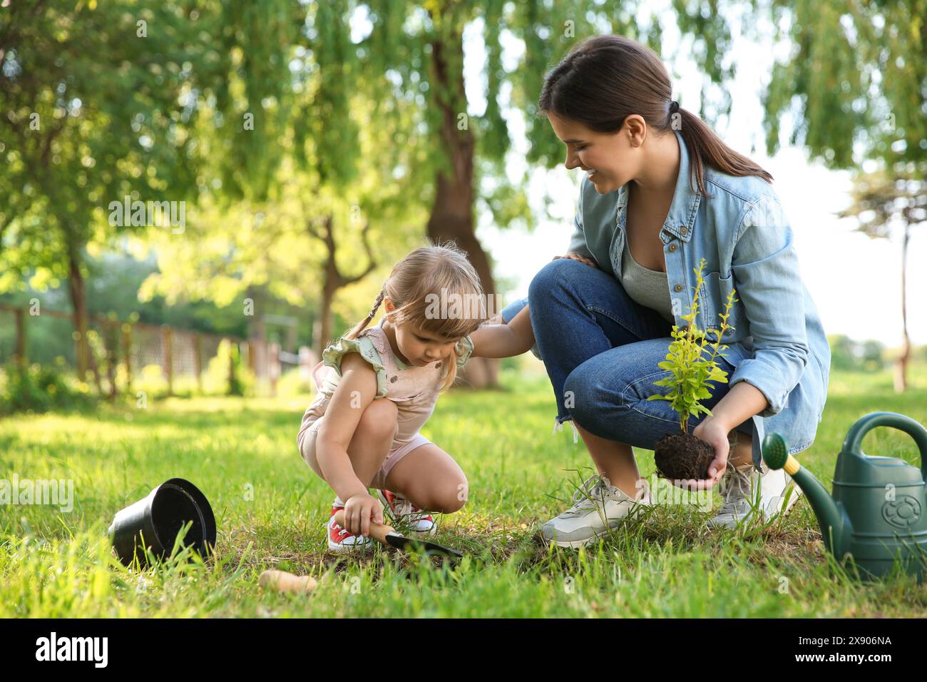 Mother and her daughter planting tree together in garden Stock Photo ...