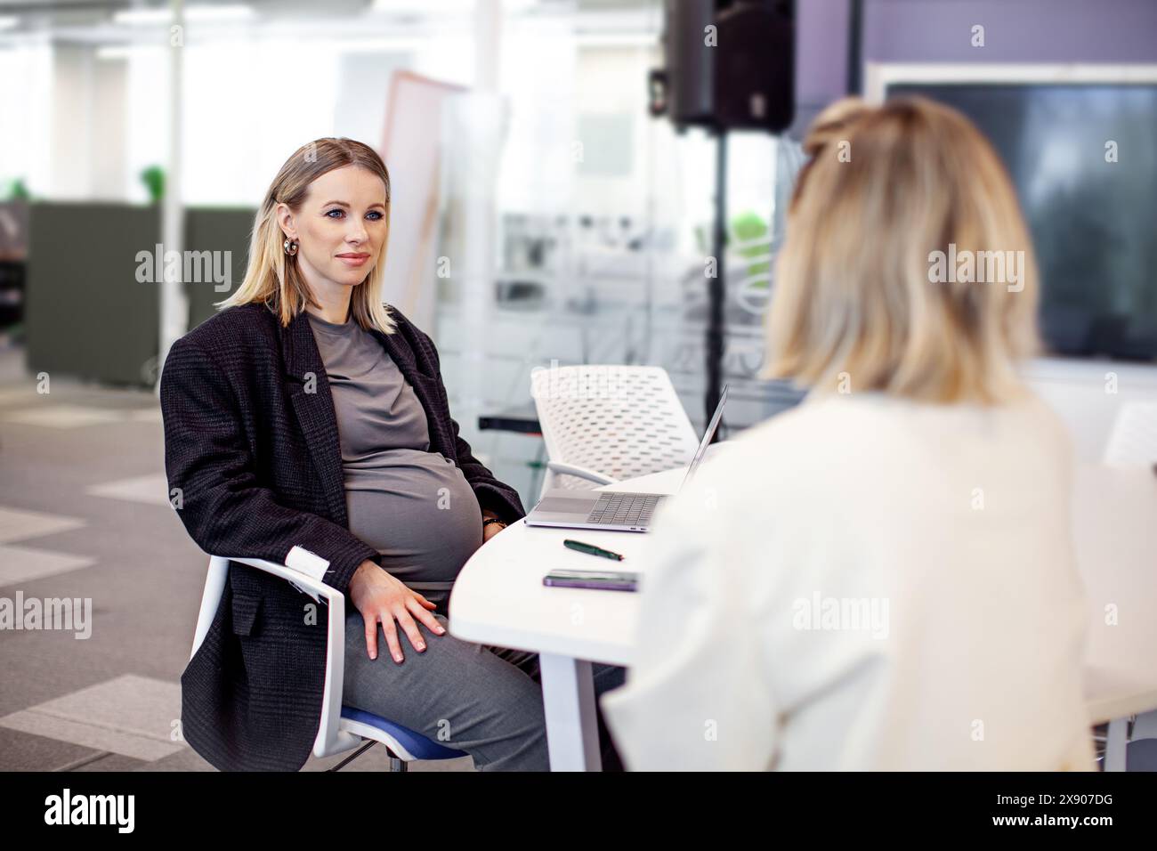 Pregnant female executive conducting an interview with an employee in ...