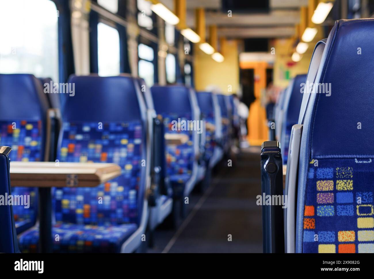 interior of a modern train or bus with rows of blue seats, and a ...