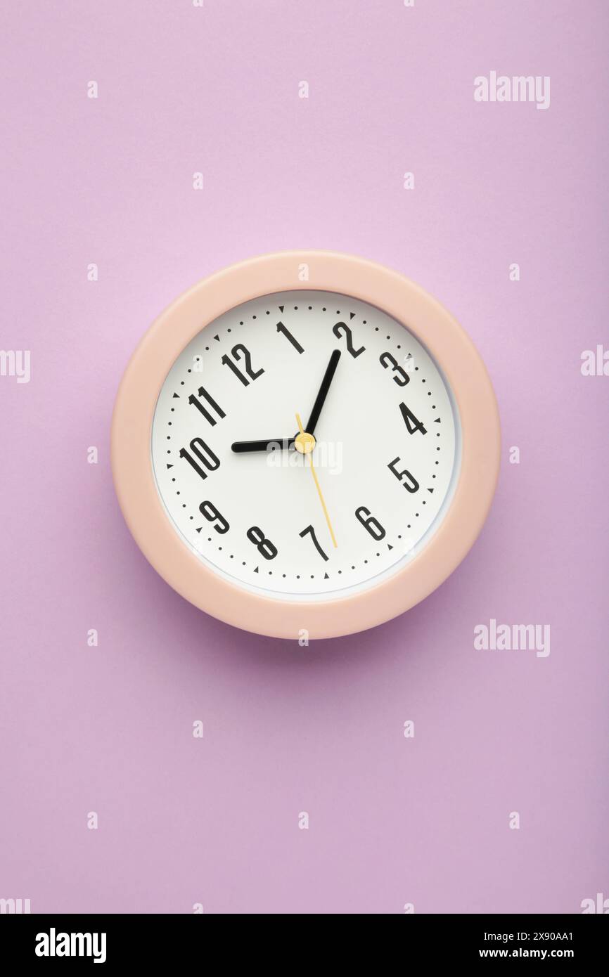 Pink clock on purple background. Vertical photo Stock Photo - Alamy