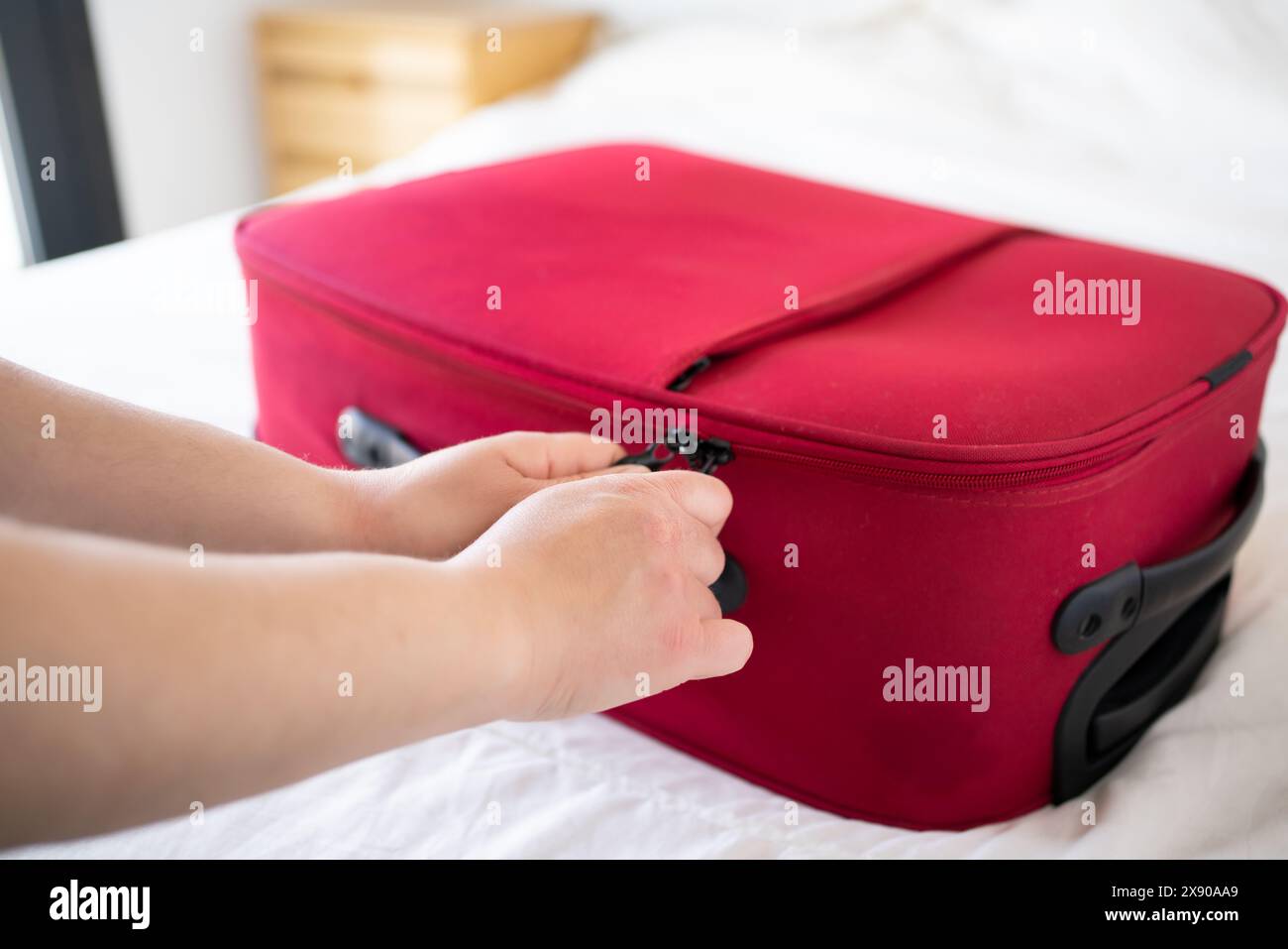 Close up hand of a young woman closing her red suitcase Stock Photo - Alamy