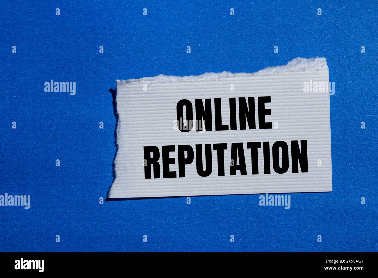 Online reputation words written on ripped white paper piece with blue ...