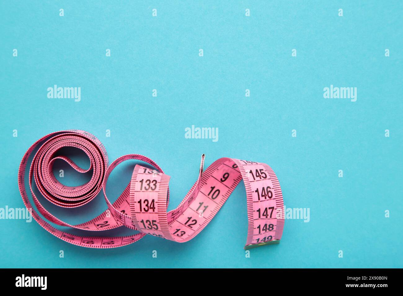 Pink plastic measure tape with metric scale over on blue background ...
