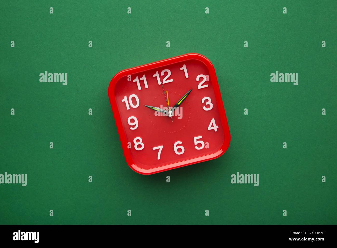 Red wall clock on green background. Top view Stock Photo - Alamy