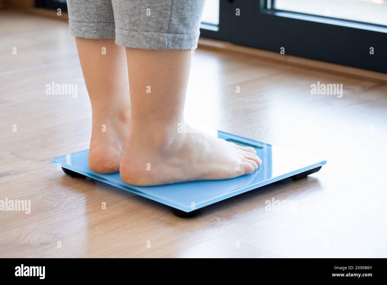 Rear view of a female checking kilogrammes getting on the scale - self ...