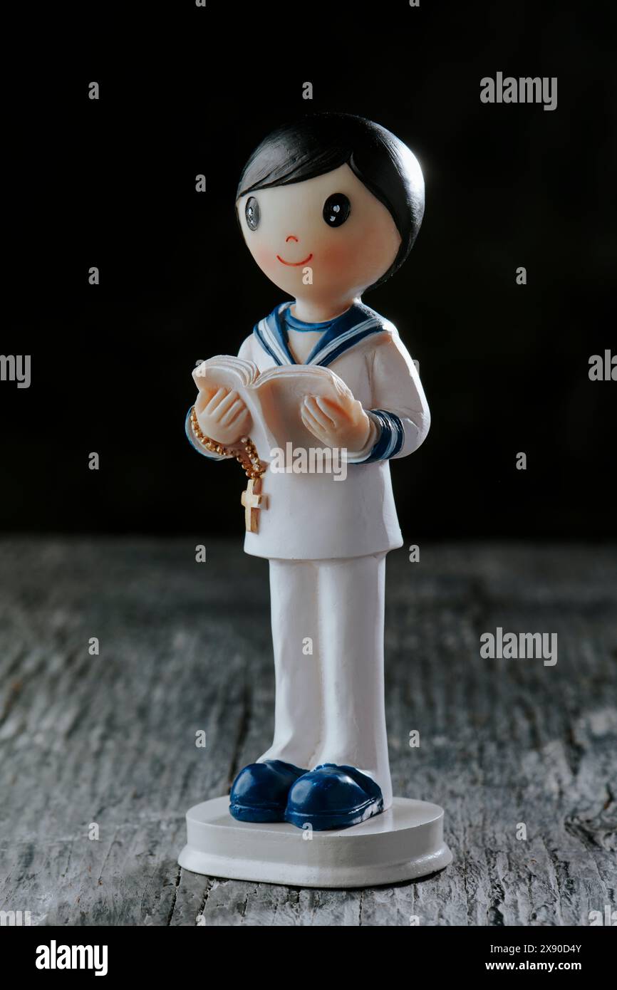 a figurine of a first communion boy, in a white sailor suit, wearing a ...