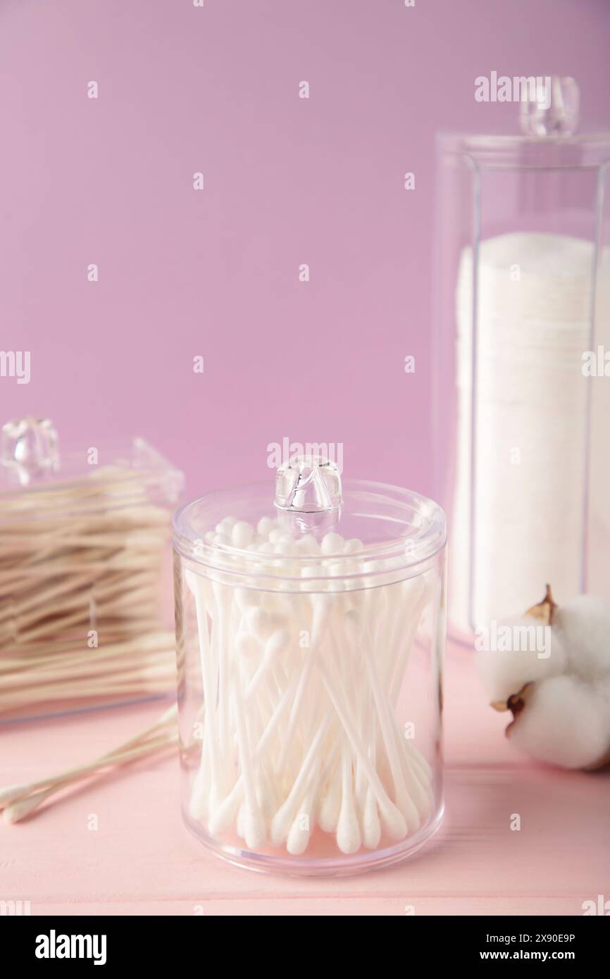 Cotton pads and cotton sticks in containers with cotton flower on ...