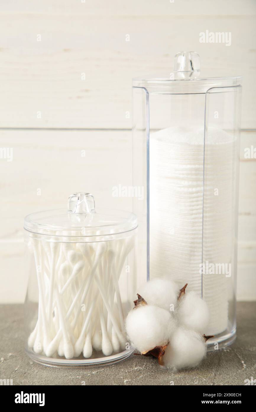 Cotton pads and cotton sticks in containers with cotton flower on white ...