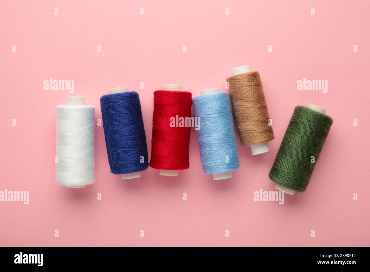 Color sewing threads on pink background, top view Stock Photo - Alamy