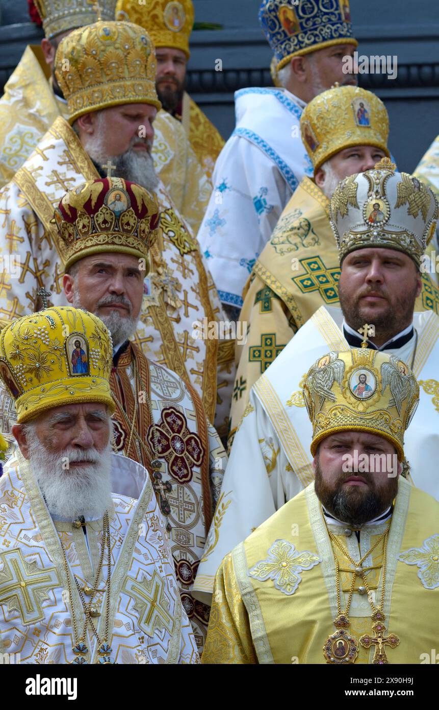 Orthodox priests in golden cassocks standing bored during prayer. Cross ...