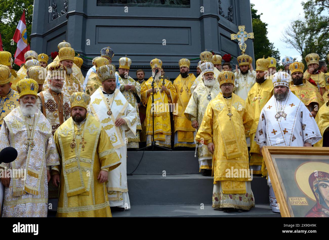 Orthodox priests in golden cassocks standing bored during prayer. Cross ...