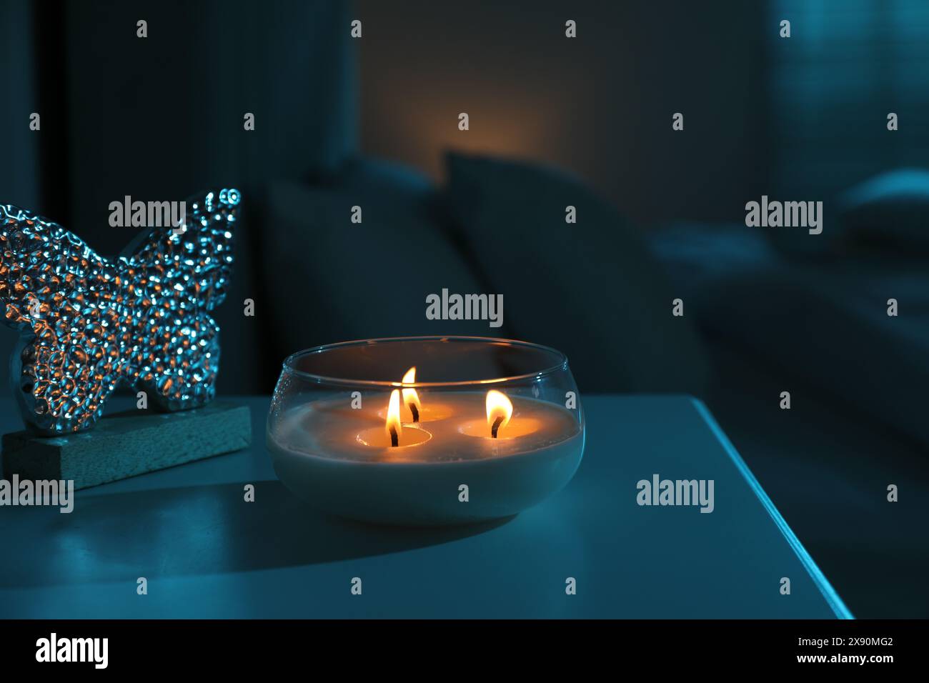Burning scented candle on bedside table in bedroom at night Stock Photo ...