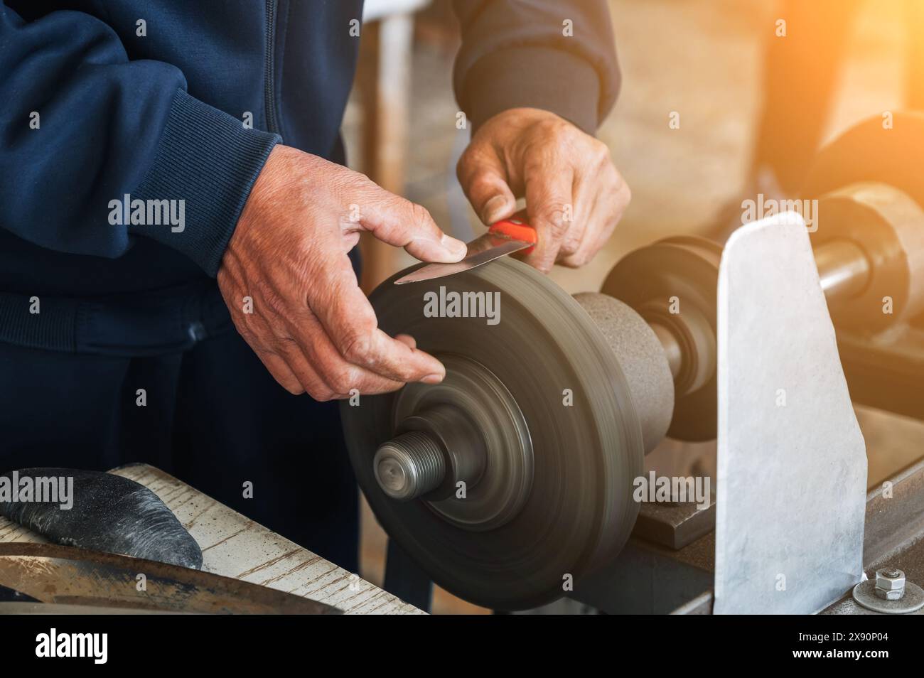 male sharpener grinder sharpens a knife blade on a sharpening machine ...