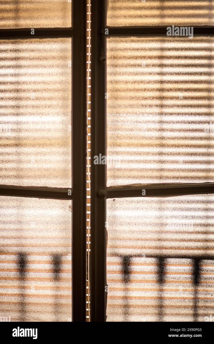 A closed balcony shutter on a glass door during a hot summer day in a ...