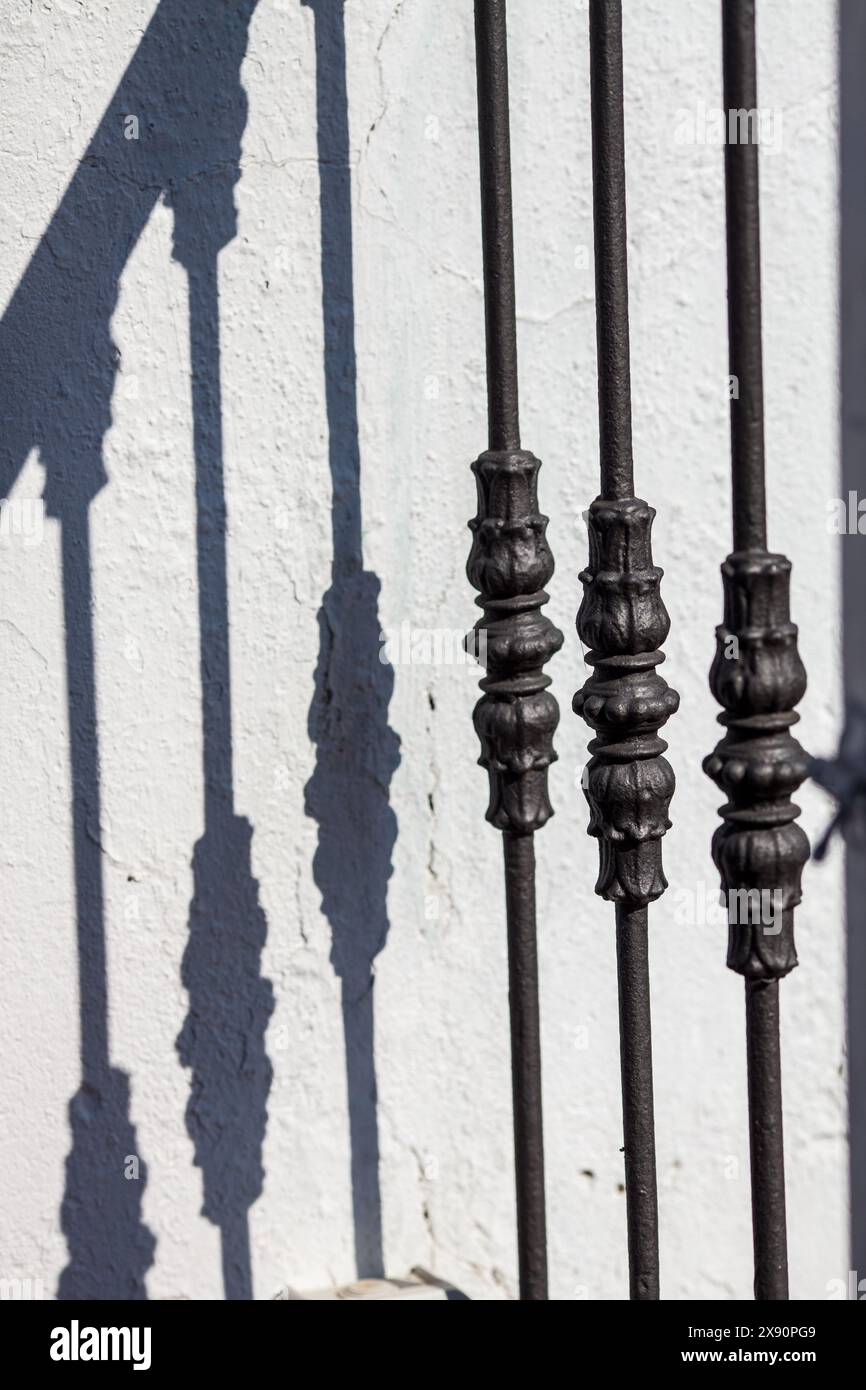 Forged iron balcony bars cast shadows on a whitewashed wall in Seville ...