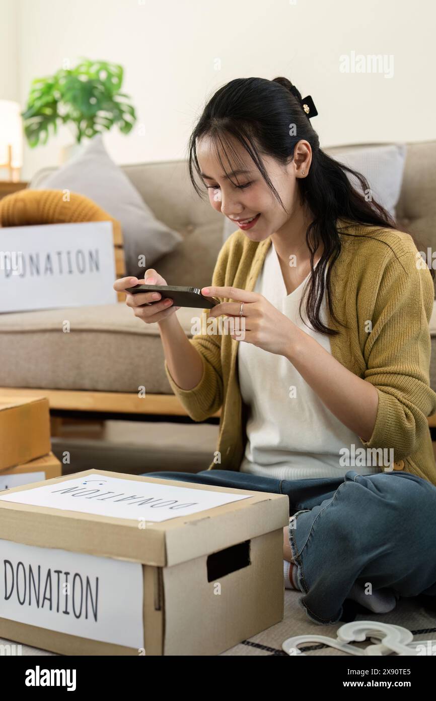 Woman taking photo of donation box at home. Concept of charity, giving ...
