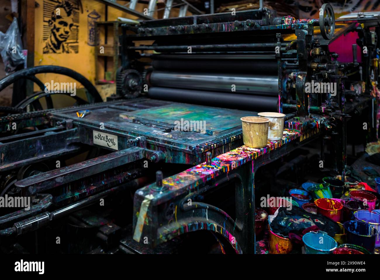 A historical letterpress machine, splattered with printing inks, is ...