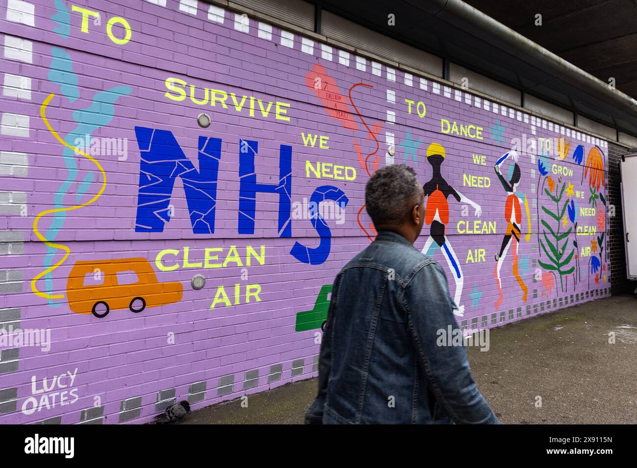 London, UK. 24th May, 2024. A woman passes a mural by Lucy Oates ...