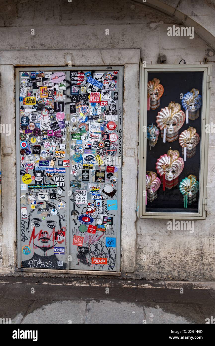 Metal door covered with stickers and window with Venetian masks on ...