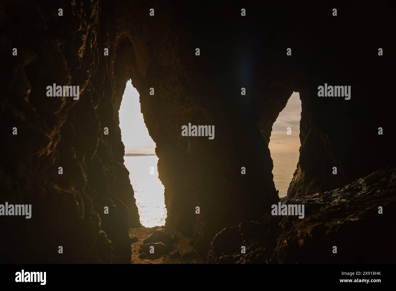 Two caves with a view of the ocean. The caves are dark and the light is ...