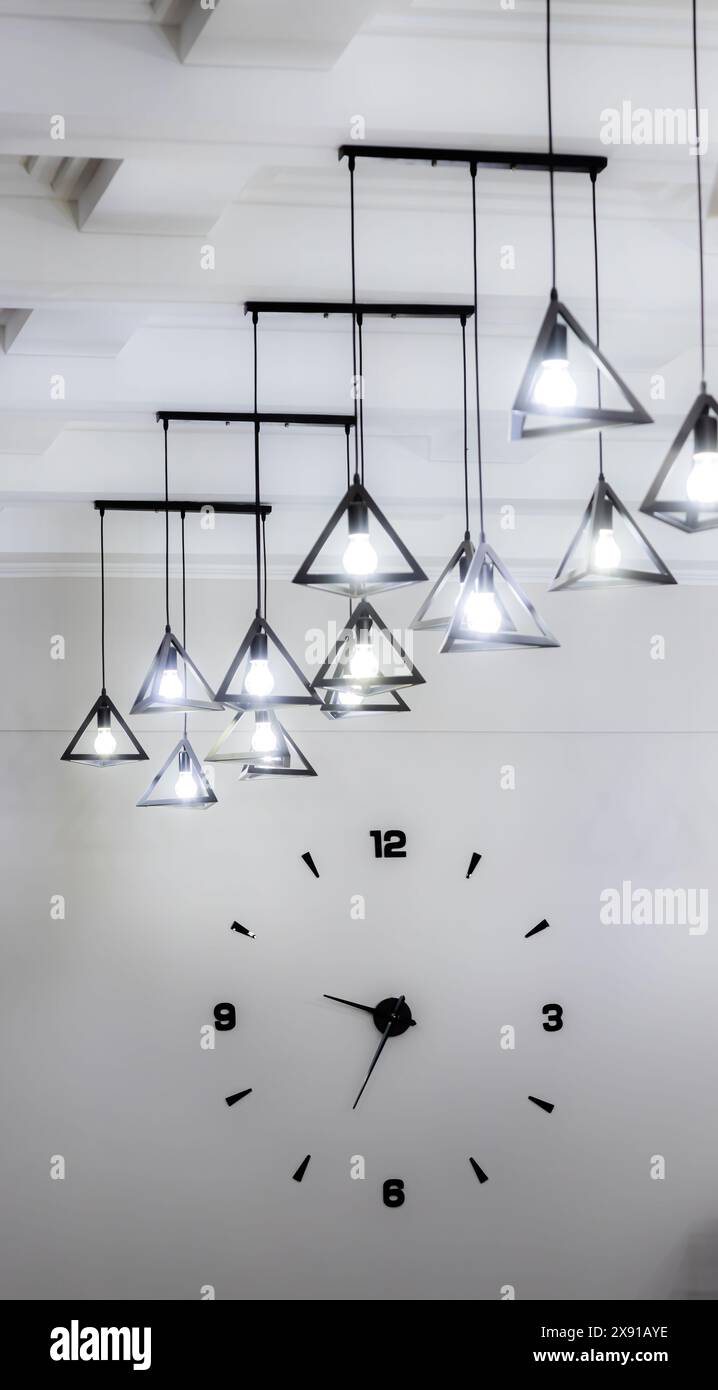 Minimalistic design of a wall clock with black numbers and a light bulb ...