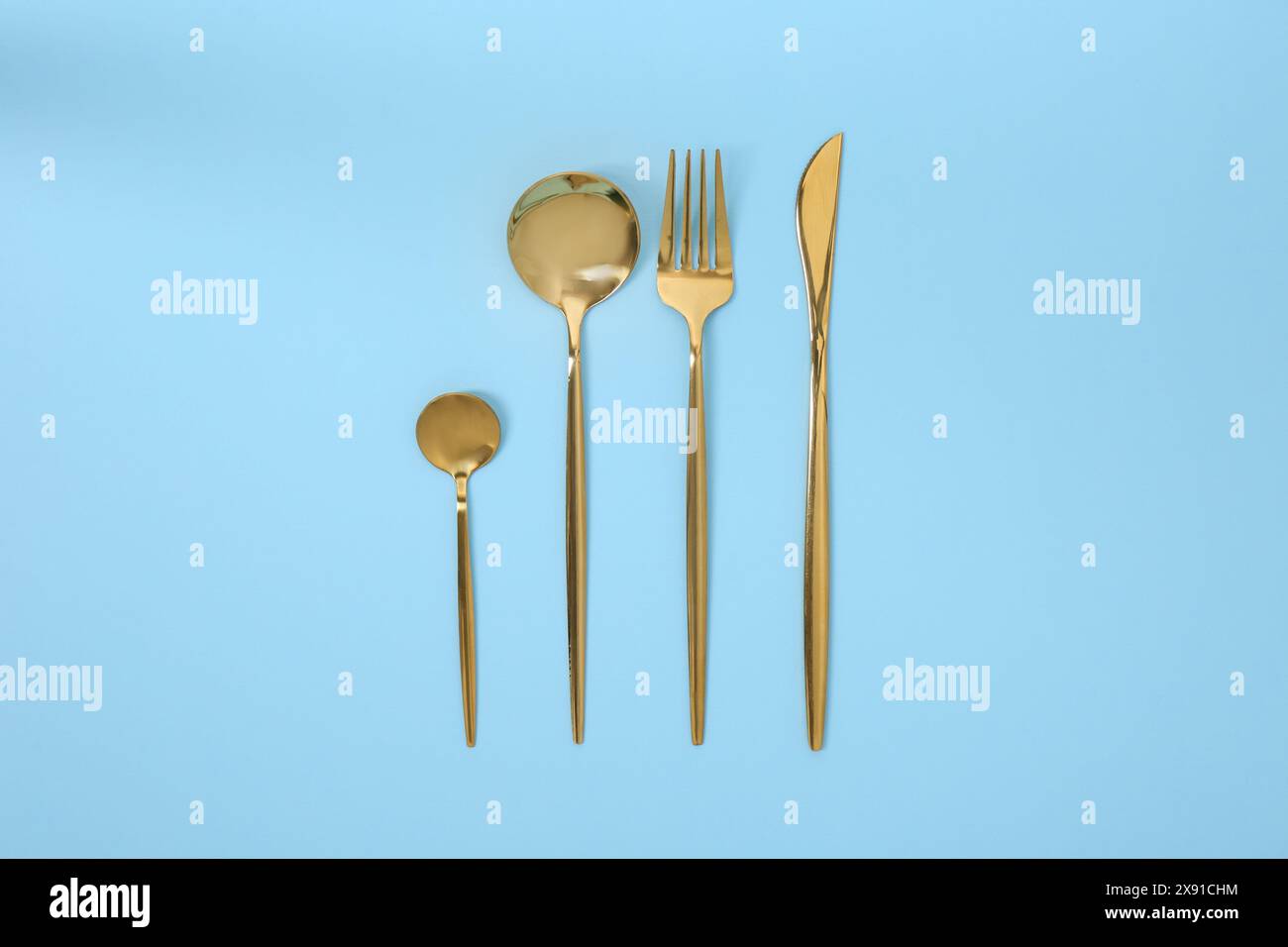 Stylish golden cutlery set on light blue background, flat lay Stock ...