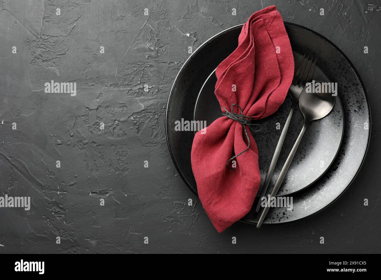 Stylish setting with cutlery, napkin and plates on dark textured table ...