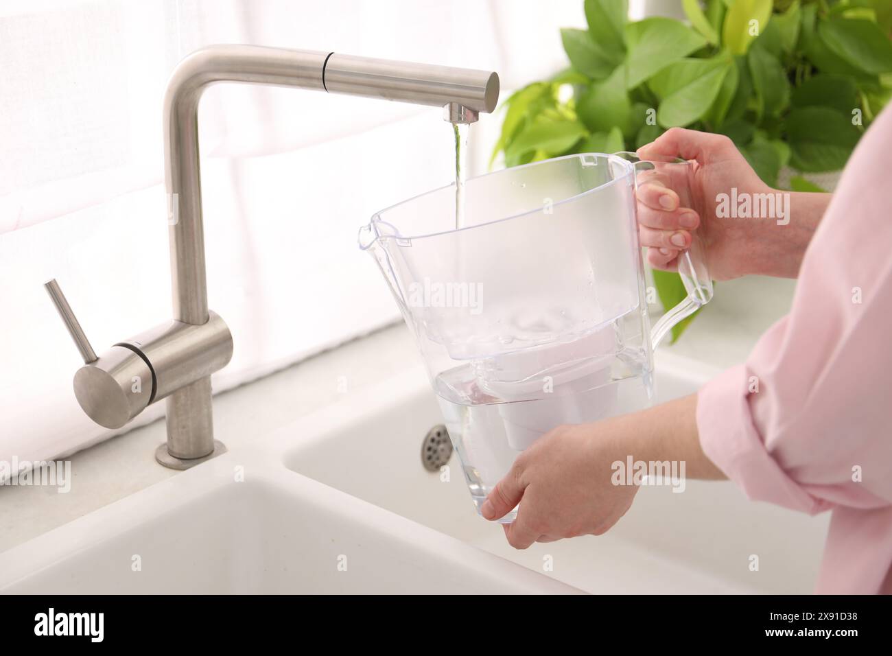 Woman filling filter jug with water from tap in kitchen, closeup Stock ...
