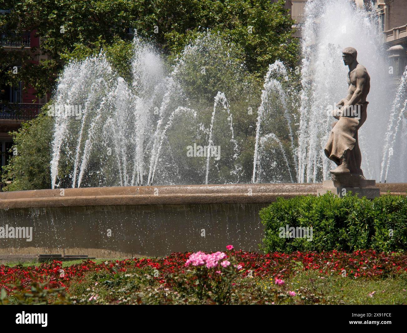 Male statue in a large fountain surrounded by splashing water and ...