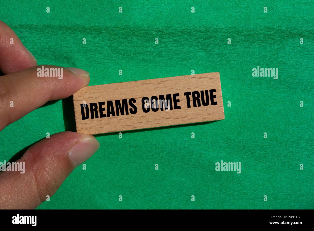 Dreams come true words written on wooden block with green background ...