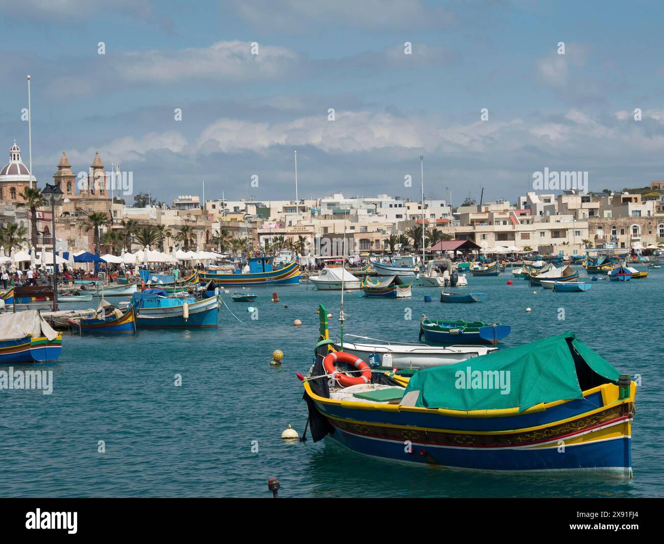 Colourful boats in the harbour against an urban backdrop with a church ...