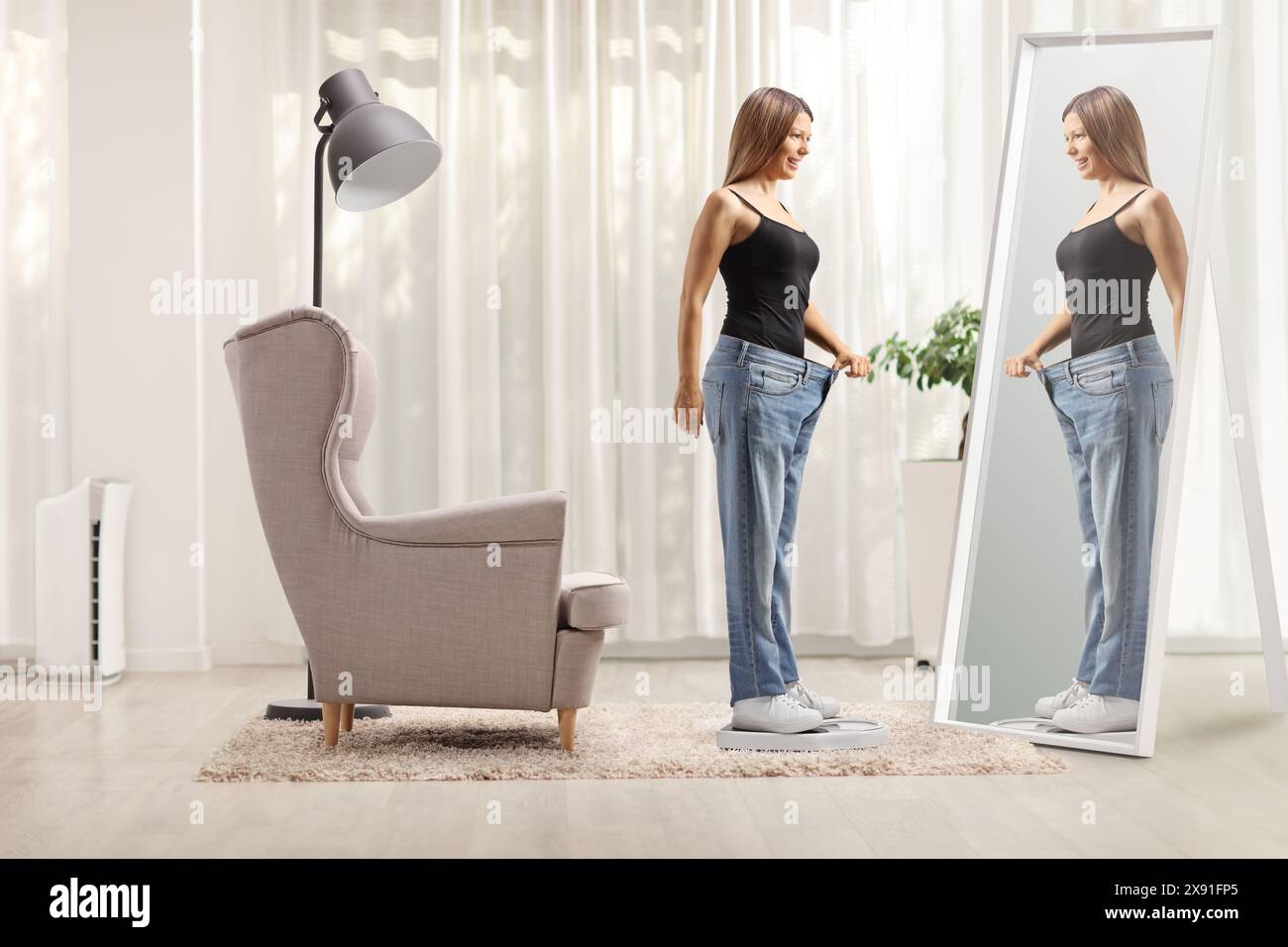 Young woman on a scale in front of a mirror at home Stock Photo - Alamy