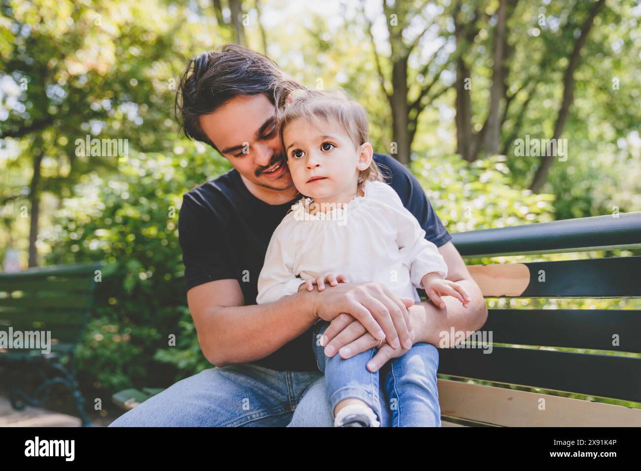 handsome young father looking at his cute daughter sit on bench Stock ...