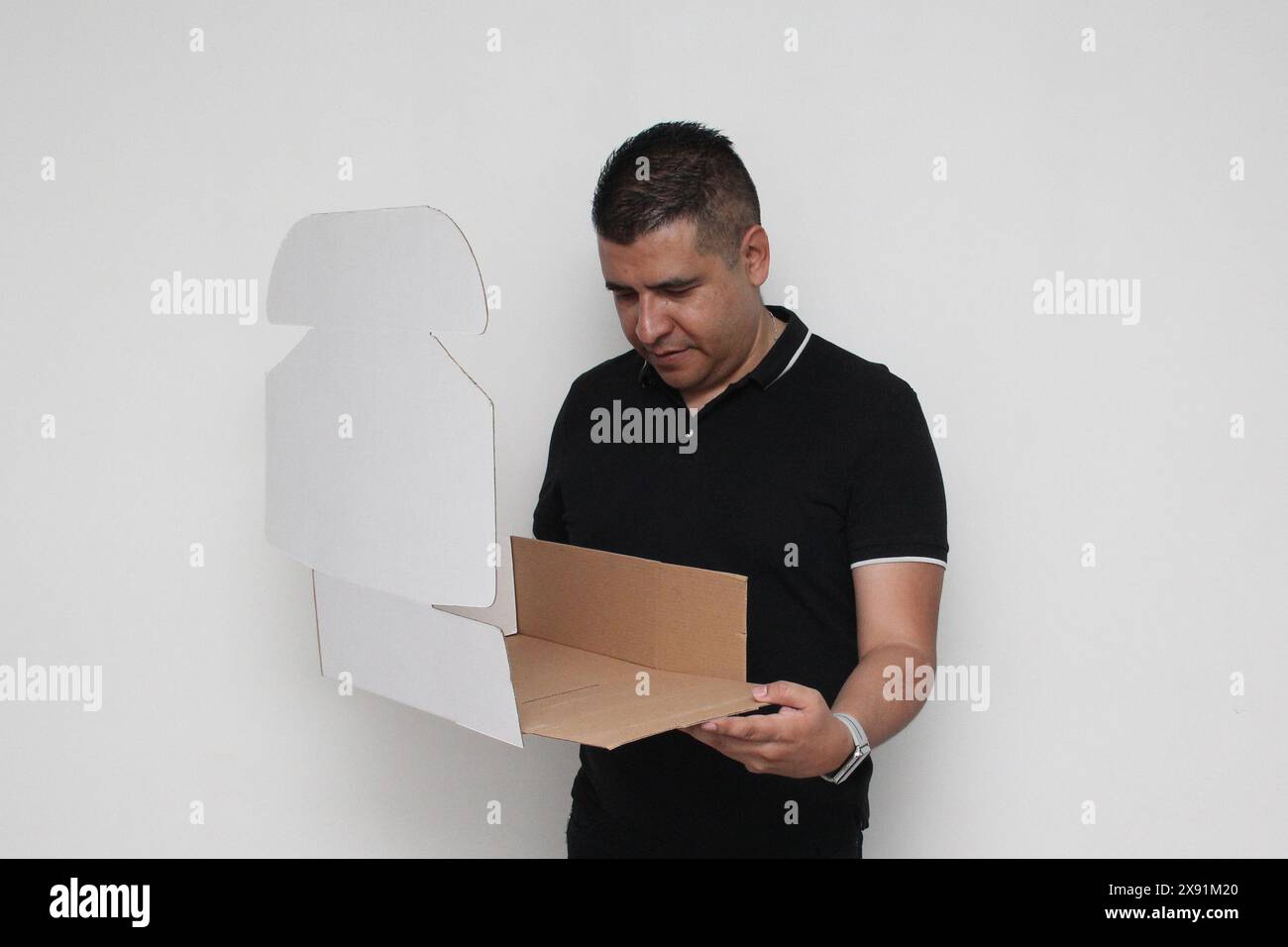 Latino adult man assembles a cardboard box following the instructions ...