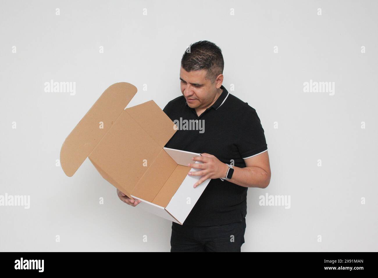 Latino adult man assembles a cardboard box following the instructions ...