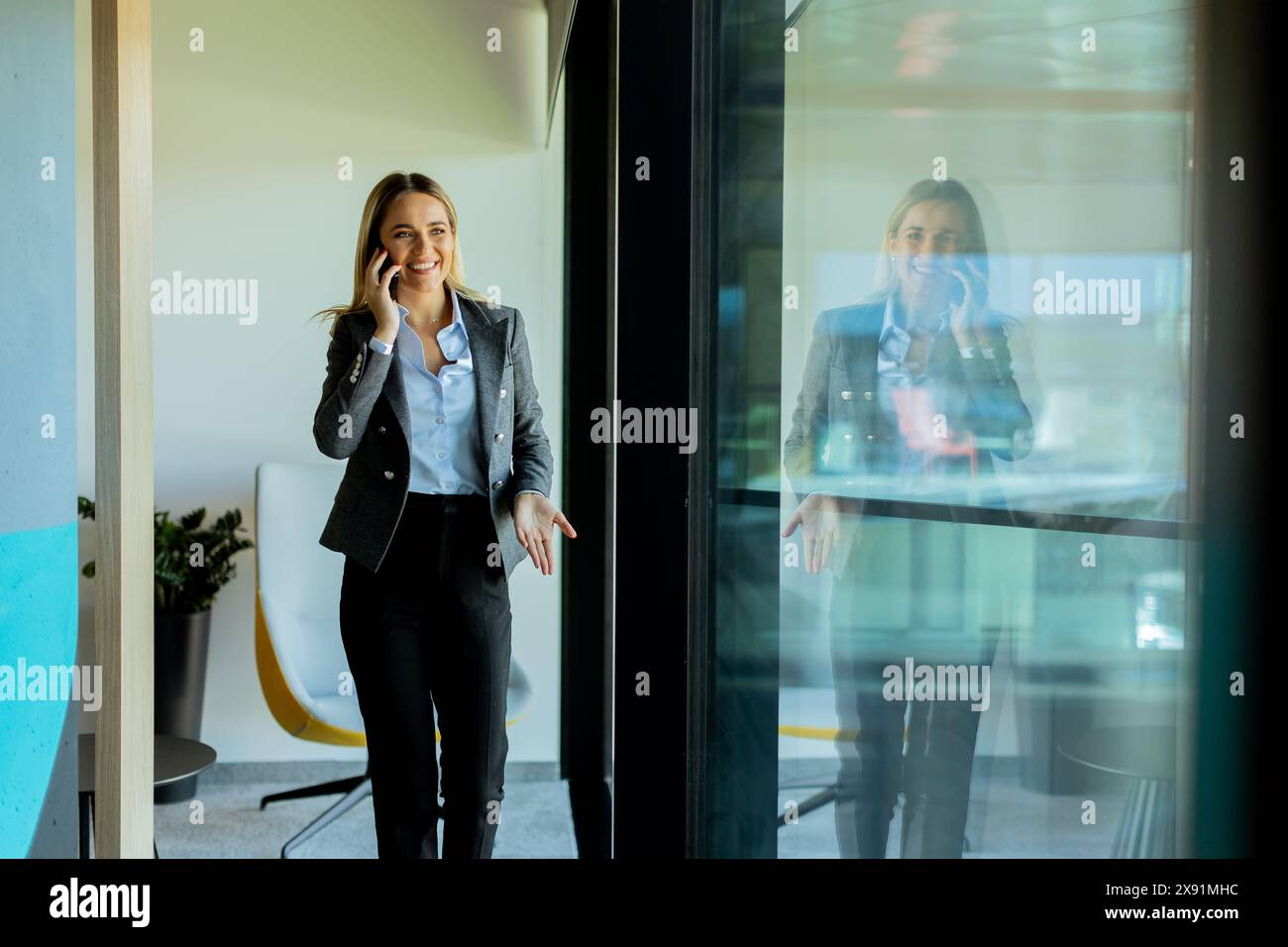 Professional woman smiles while speaking on her phone in a bright ...