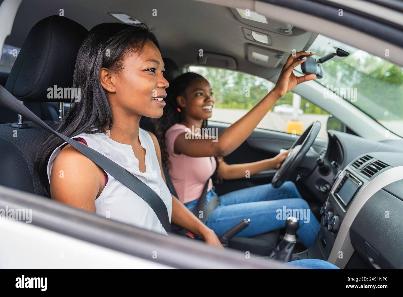 Young black teenage driver seated in her new car with her mother Stock ...