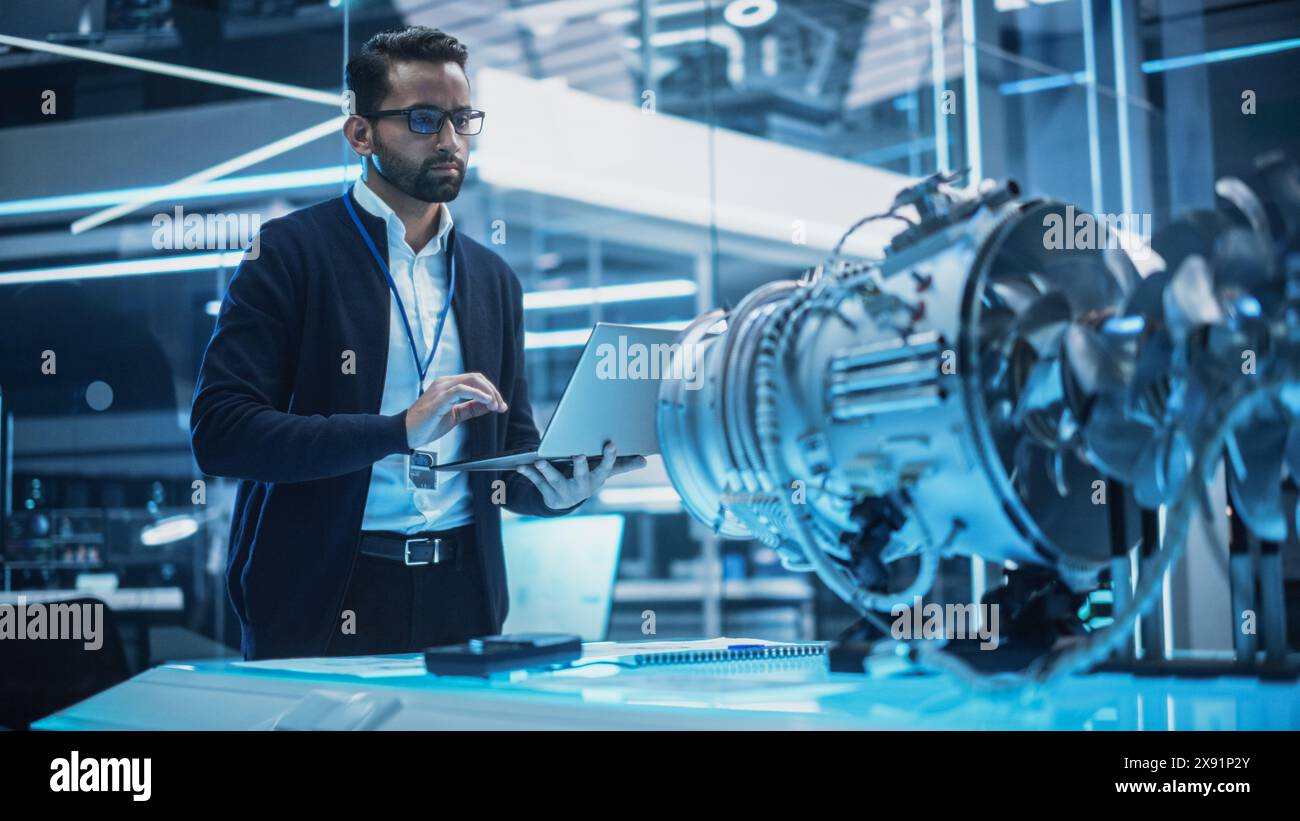 Young Industrial Engineer Working on a Futuristic Jet Engine, Standing ...