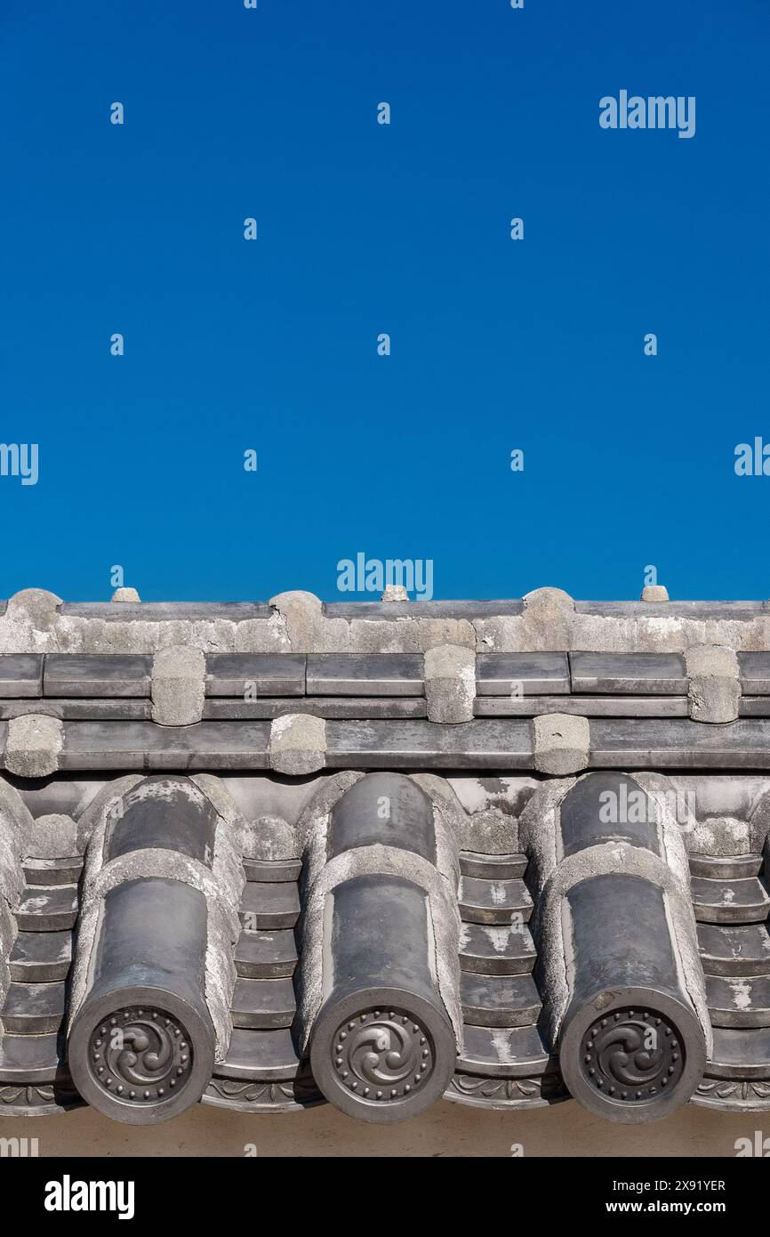 Japanese traditional grey roof tile with old spiral motif and blue sky ...