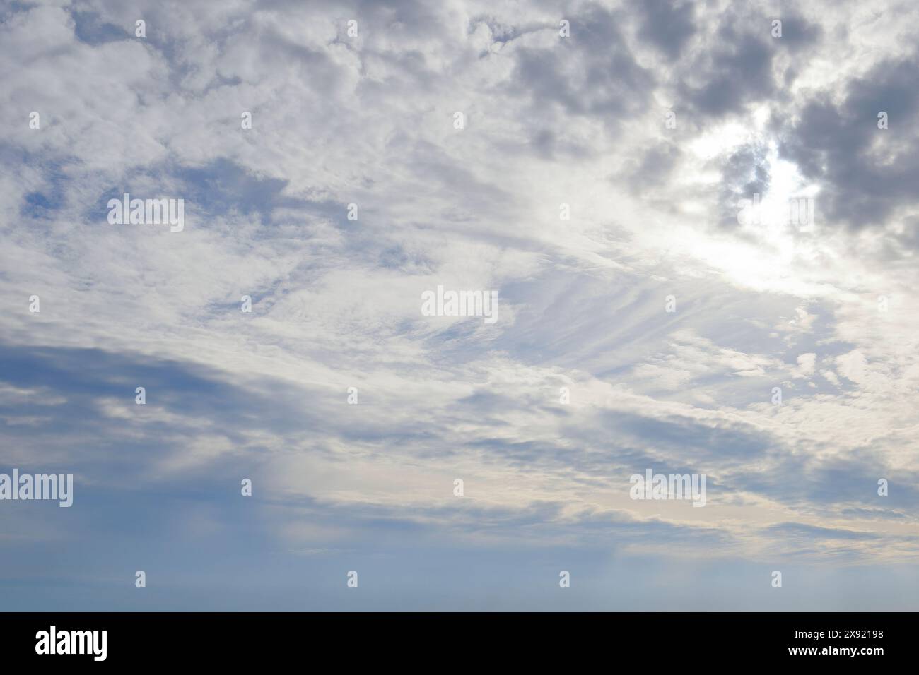A cloudy sky with blue patches, the sun shining through the clouds from ...
