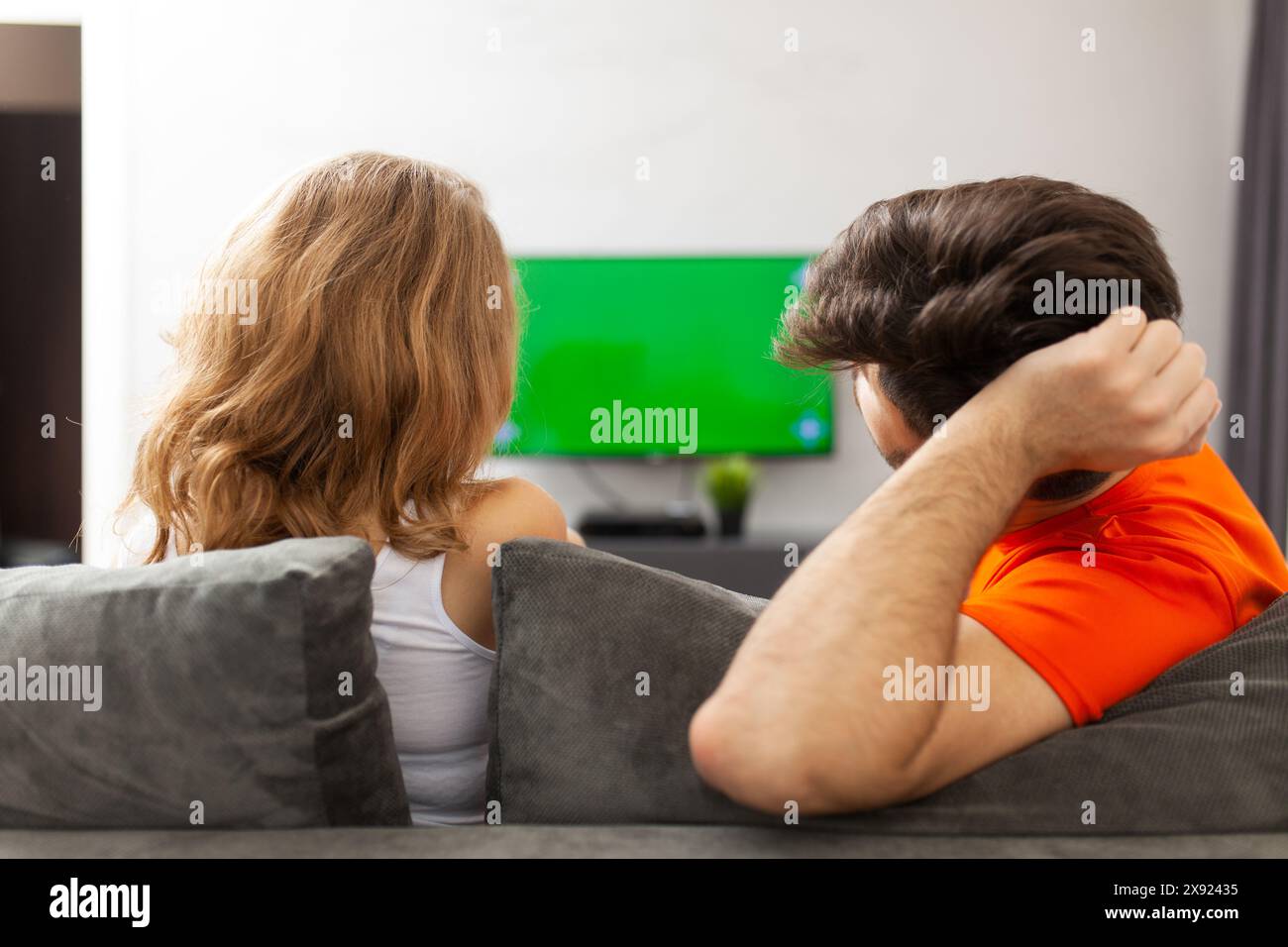 Casual young couple enjoying leisure time by watching a television with ...