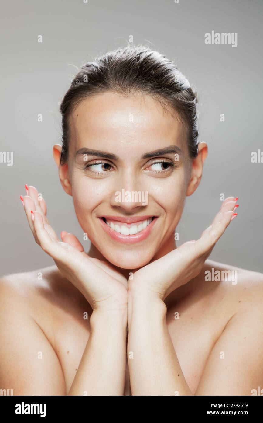 Portrait of a cheerful young woman with a radiant smile, looking away ...